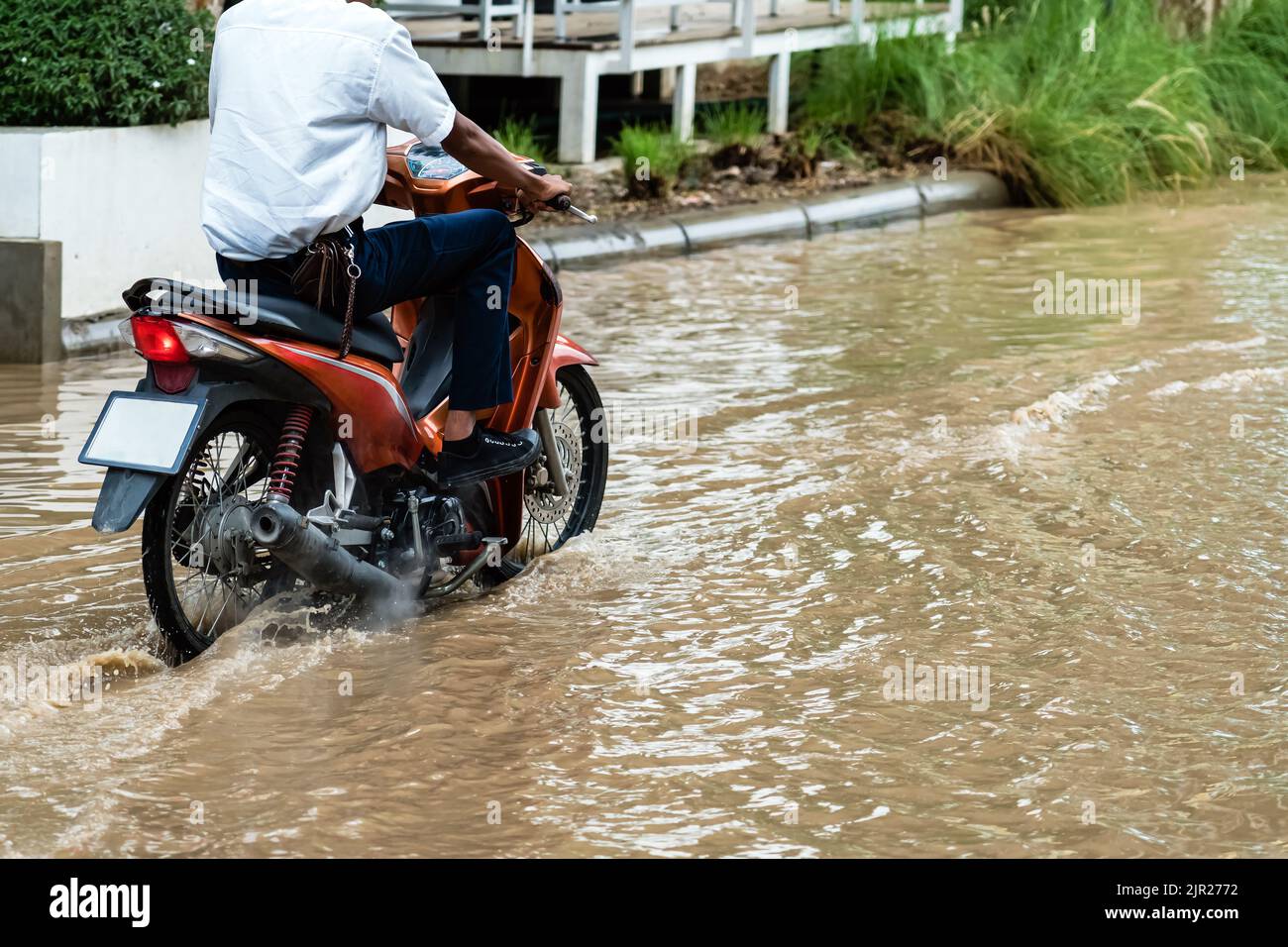 Man ride motorcycle passing through flooded road. Riding motorbike on ...