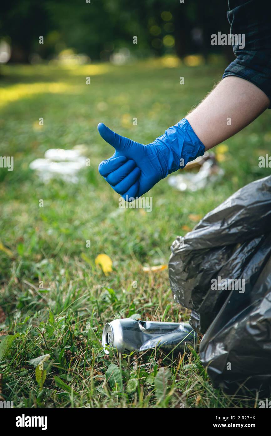 A man's hand in a glove cleans up garbage in the forest Stock Photo - Alamy