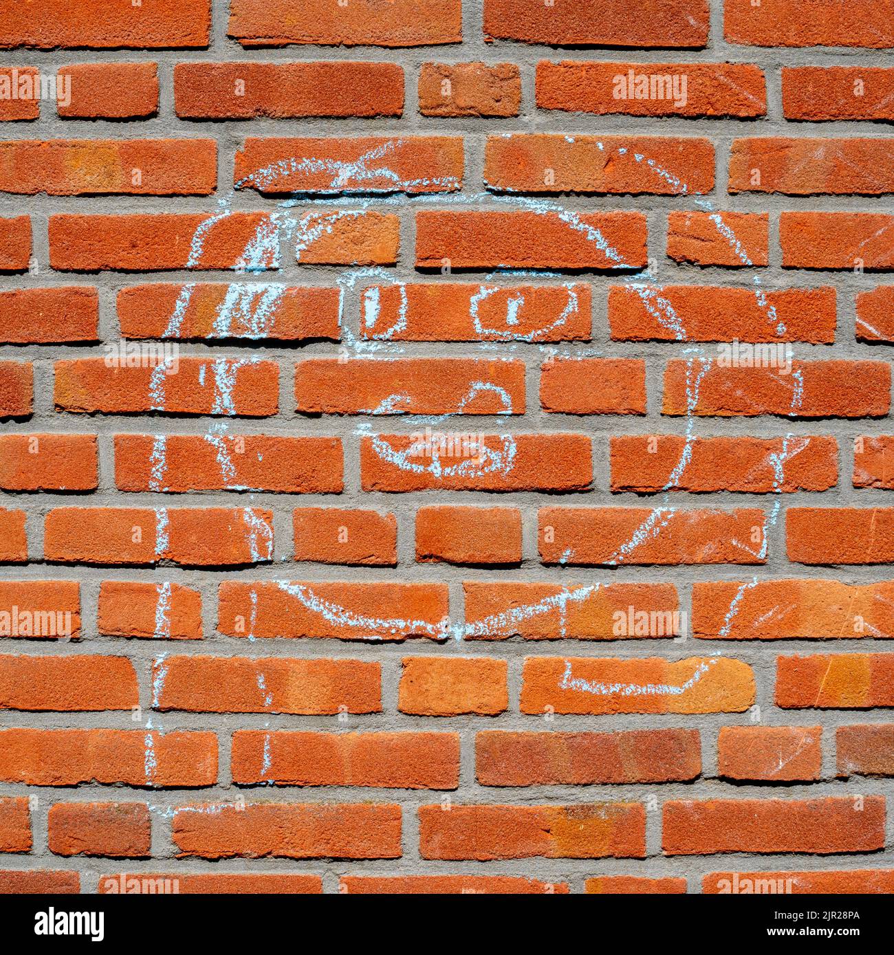 Children's chalk drawing of a face on the wall Stock Photo - Alamy