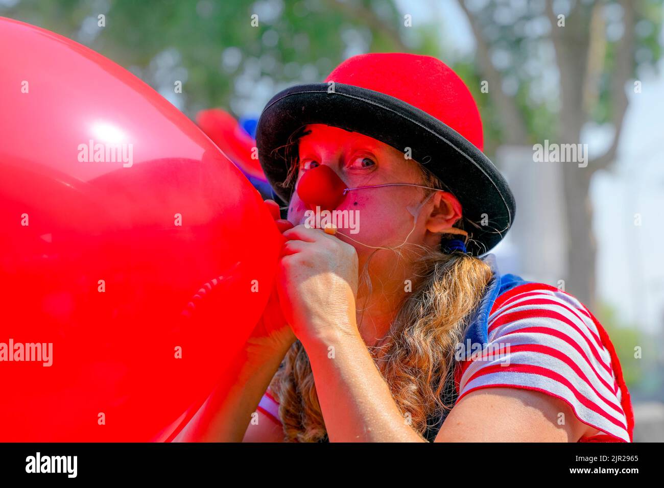 Clown blowing up red balloon Stock Photo - Alamy