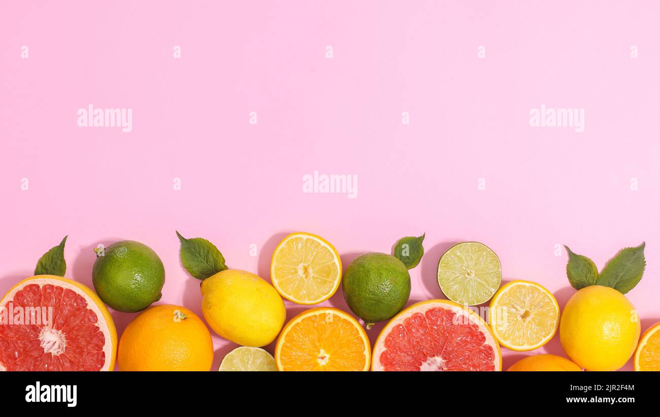 Citrus fruits with green leaves on bottom on pastel pink background ...