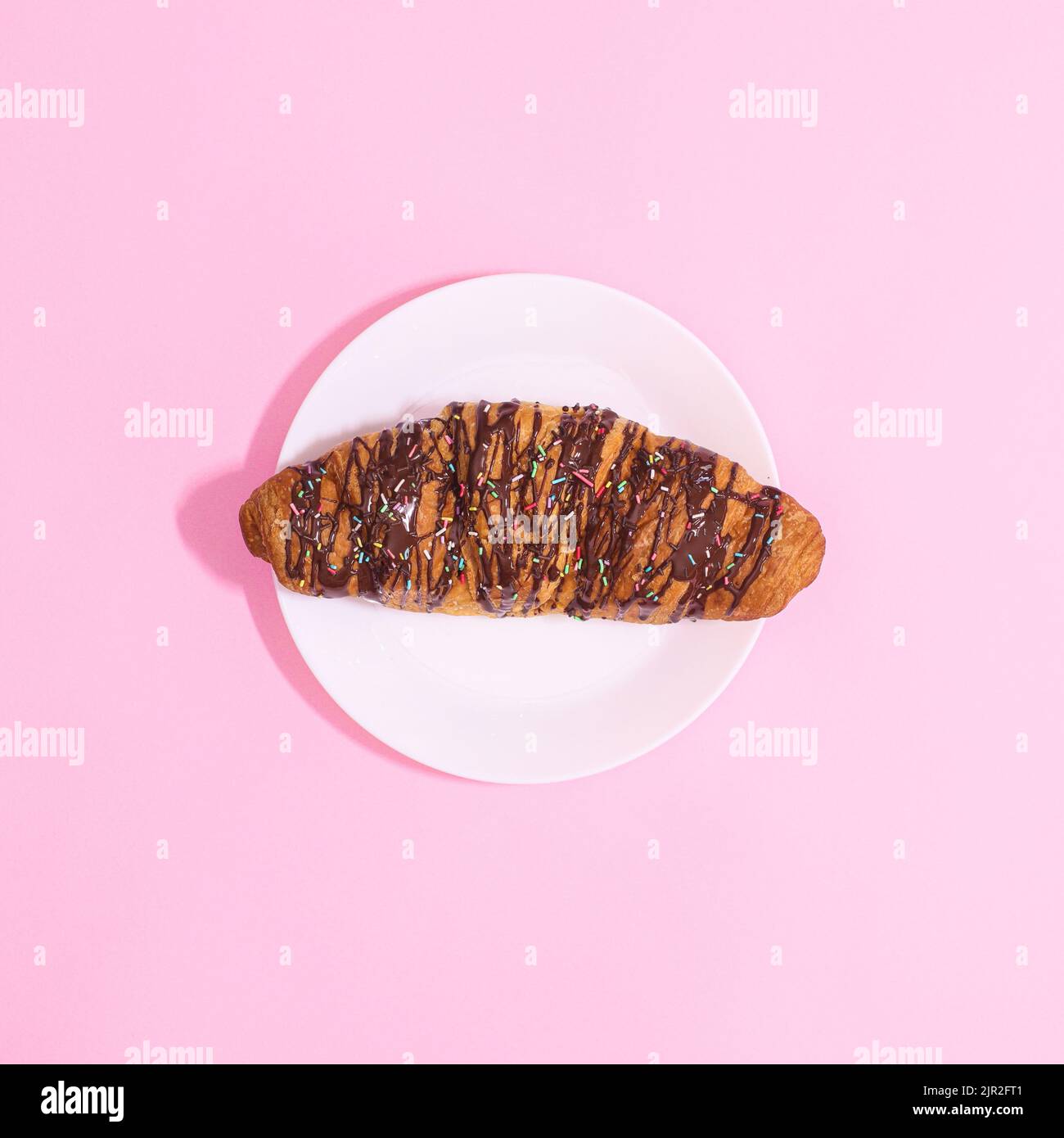 Delicious chocolate croissant on plate on pastel pink background. Flat ...