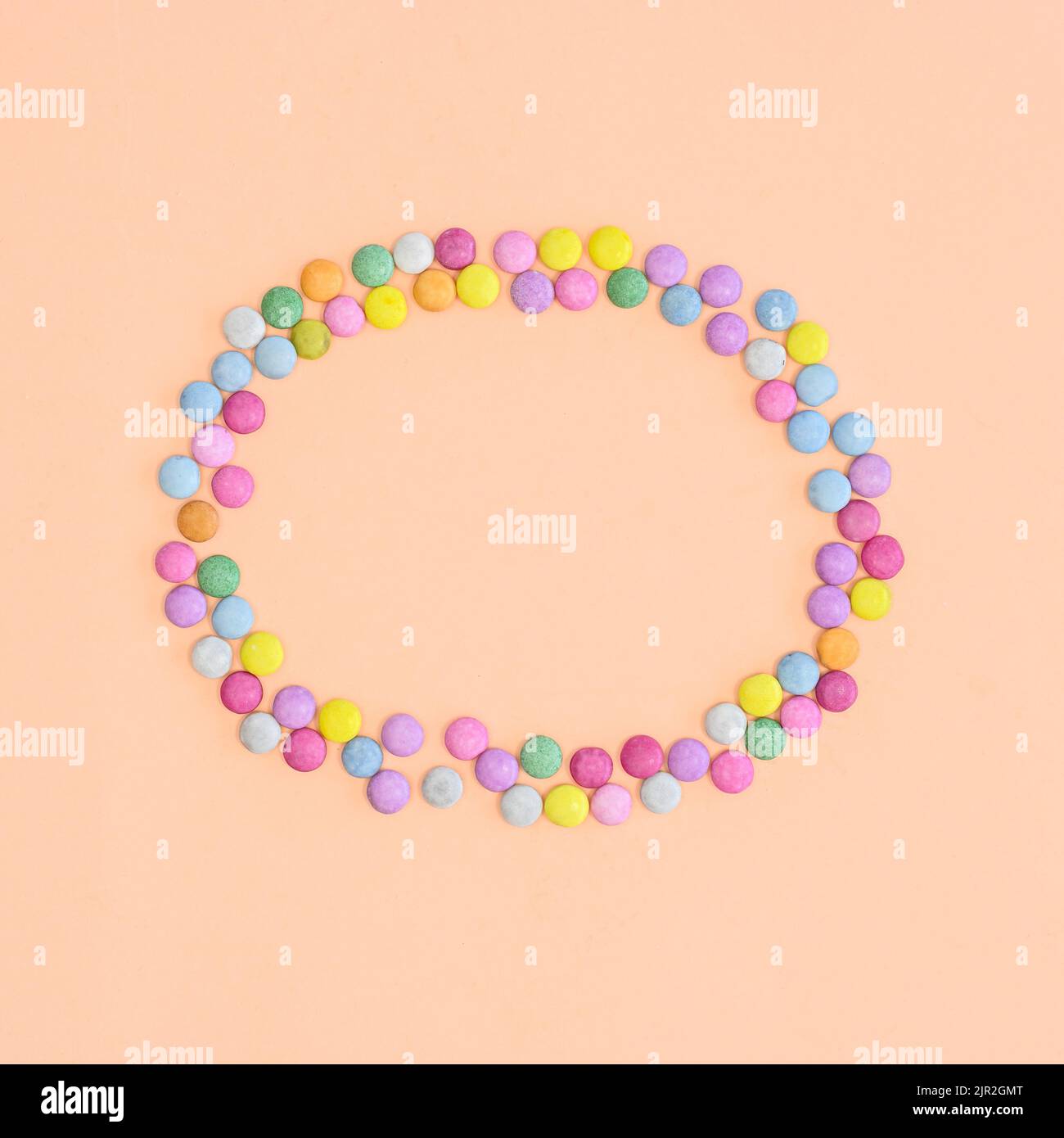 Colorful candies make frame on beige background. Flat lay Stock Photo ...