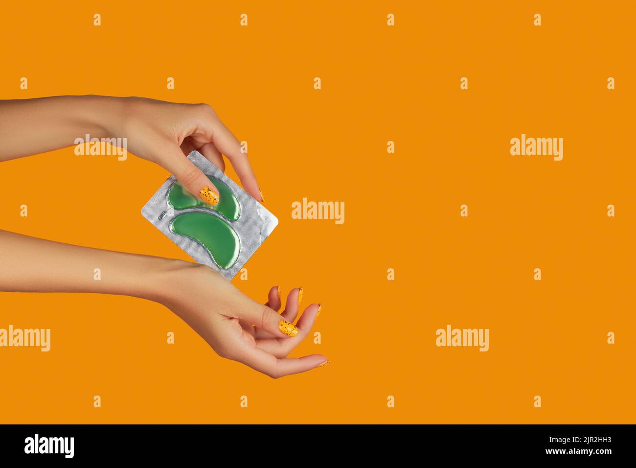 Womans hands holding eye patches on orange backgound. Face care beauty ...