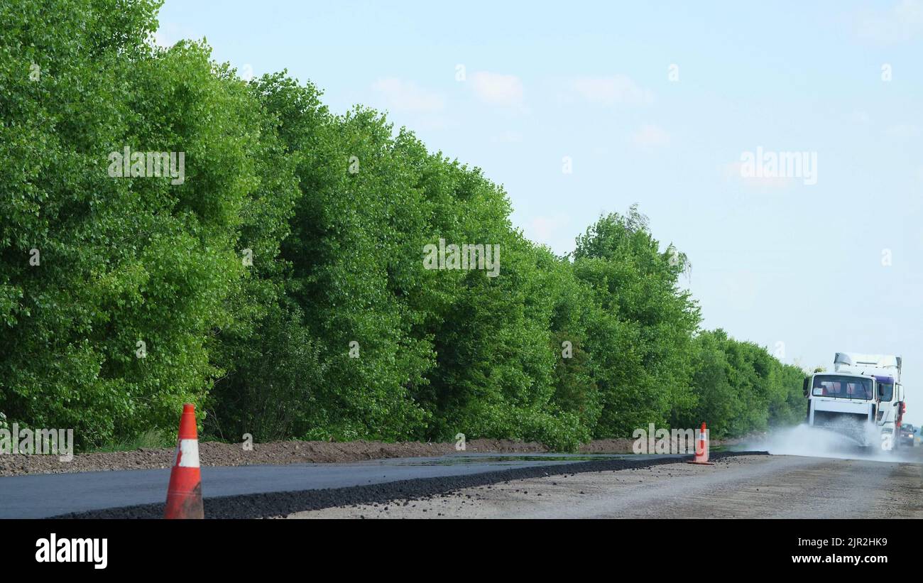 repair of a highway, Special watering machine sprinkles water on new ...