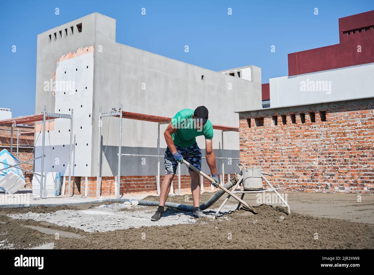 Full length of male worker shoveling sand-cement mix while working at ...