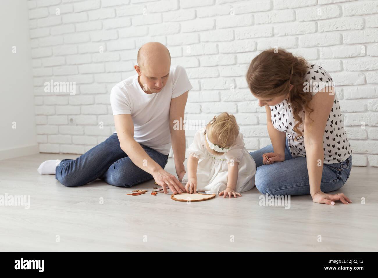 Child girl with cochlear implant plays at home with mother and father ...