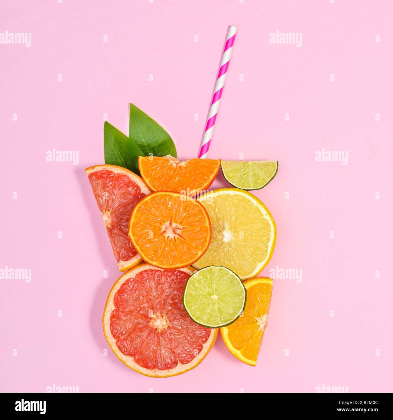 Creative glass of juice made of citrus fruits with straw on pastel pink ...