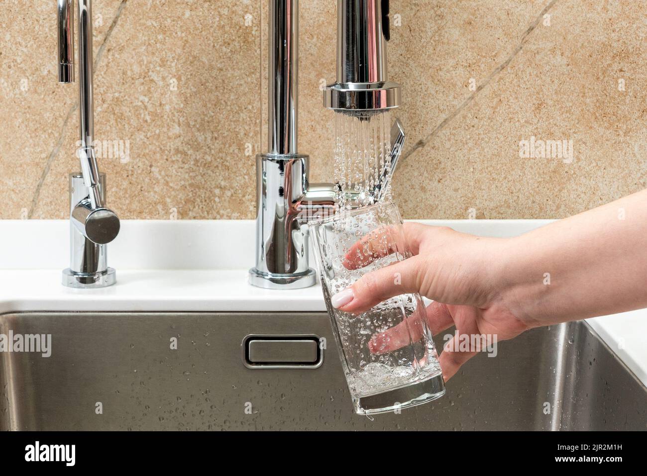 A woman's hand holds a glass of water and draws it from the tap Stock ...