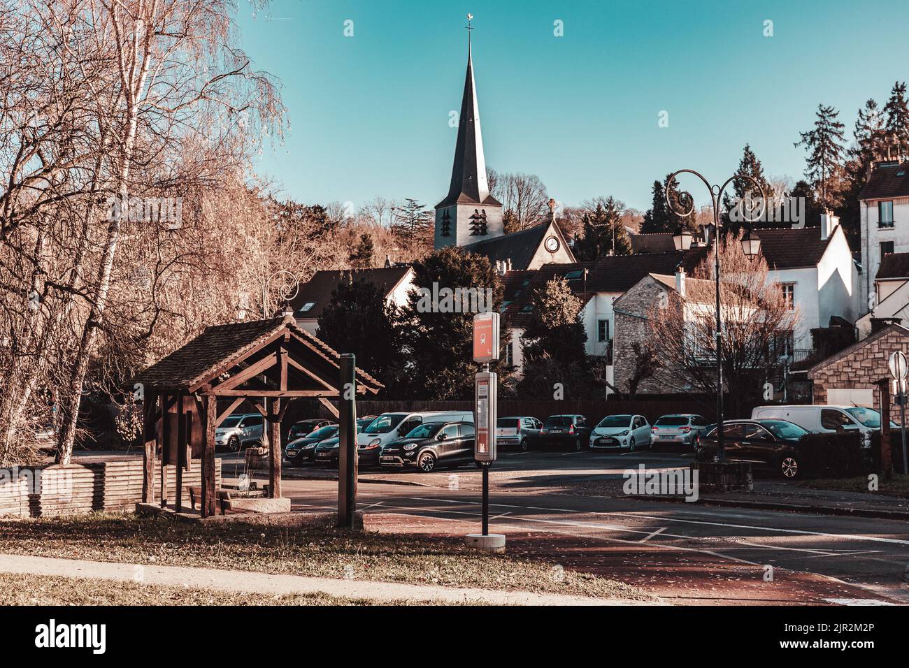 A cityscape with a church, homes, and cars with blue sky in the ...