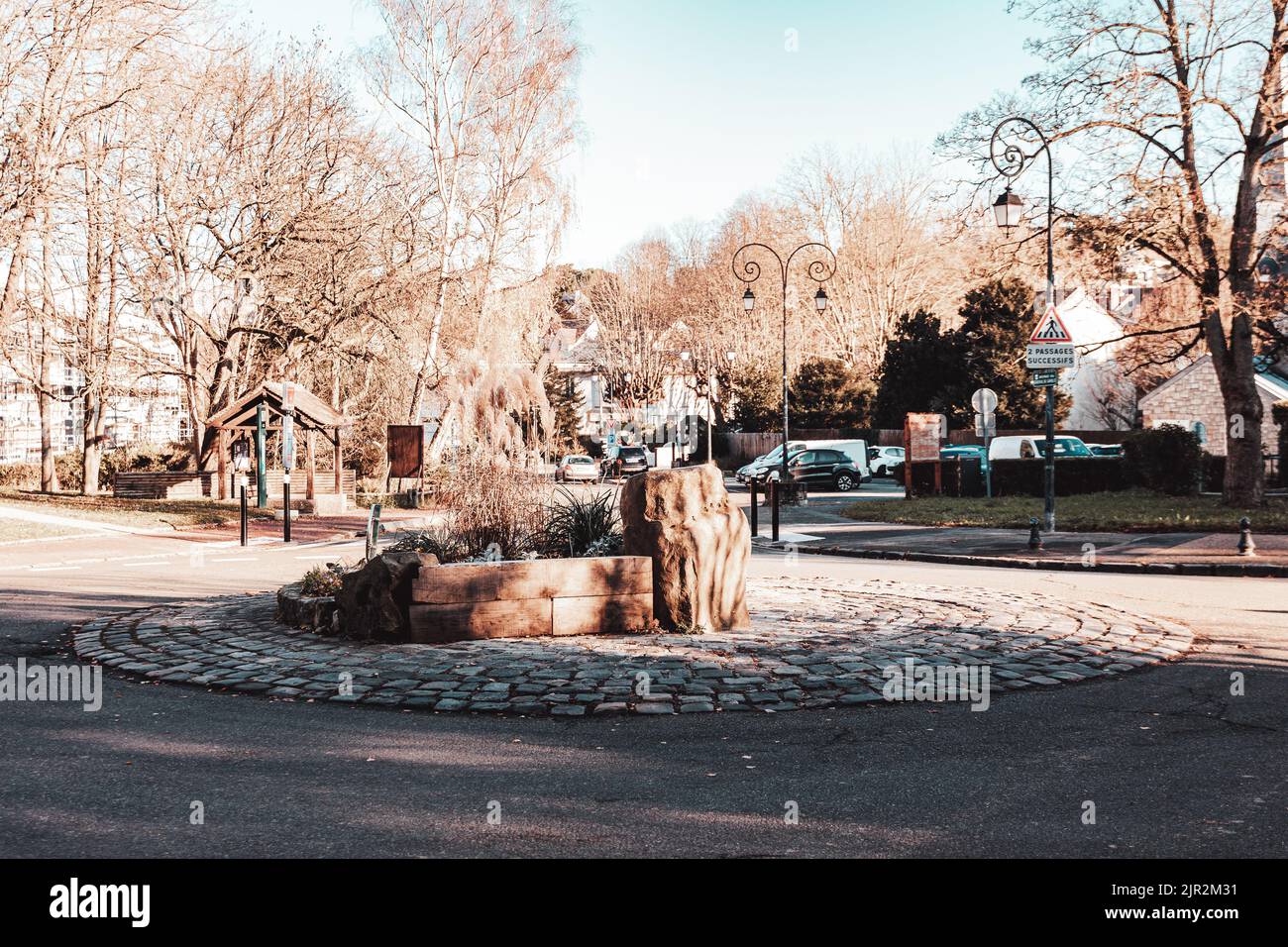A central park view with wooden objects, lamps and deciduous trees in ...