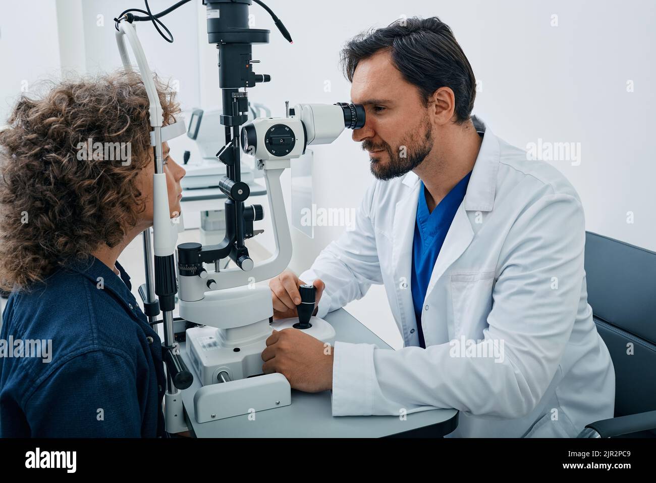 Male optometrist doing sight test for male child at modern ...