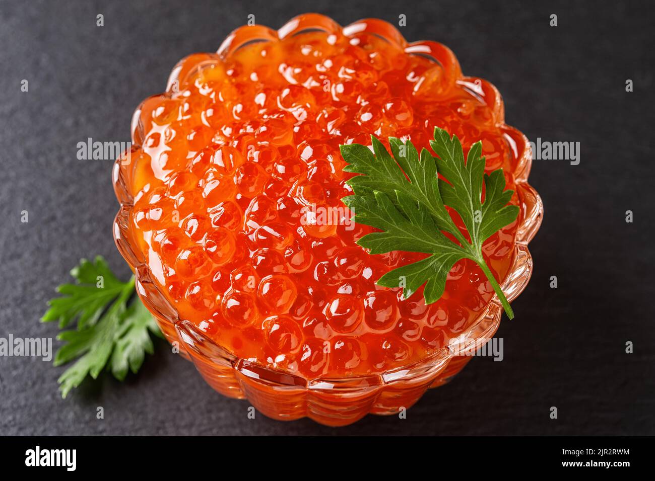 Salmon red caviar in a glass bowl on a black background. Crystal dish ...