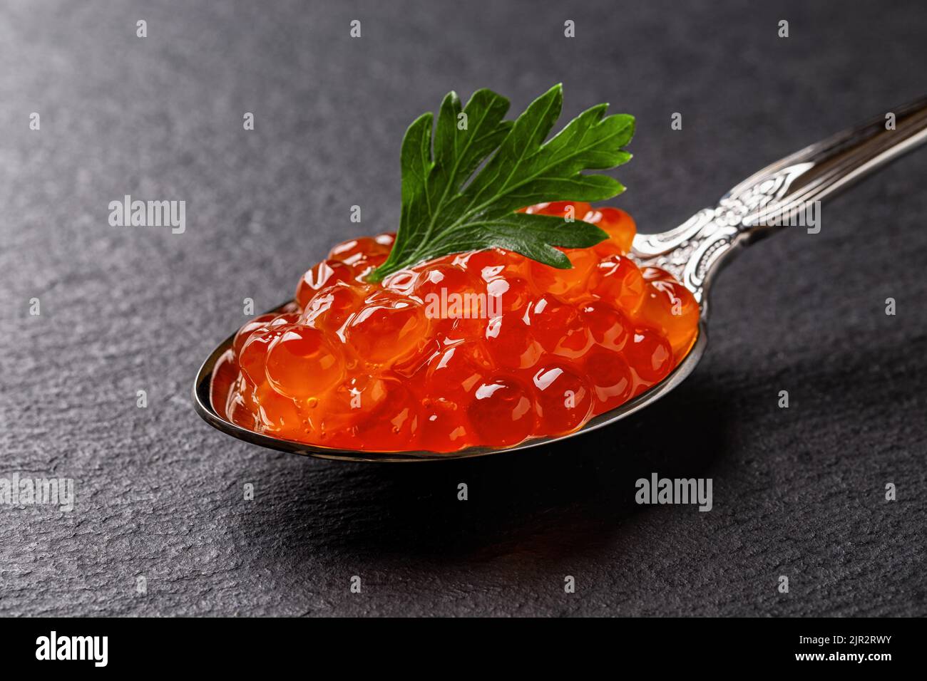 Salmon red caviar and parsley in a spoon macro. Vintage spoon full of ...