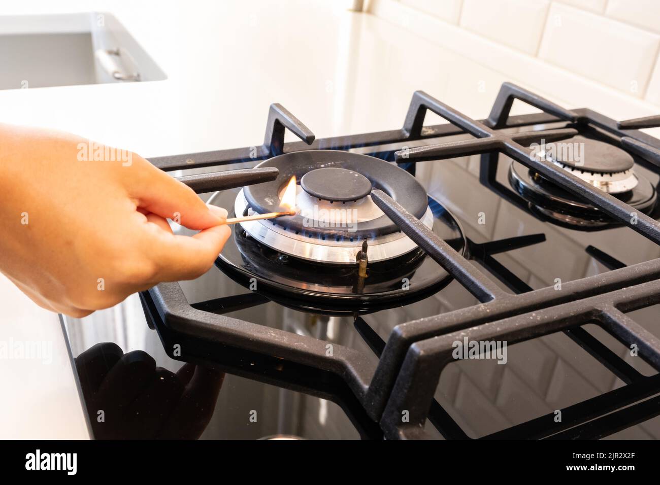 Hand with a match ignites a gas burner Stock Photo - Alamy