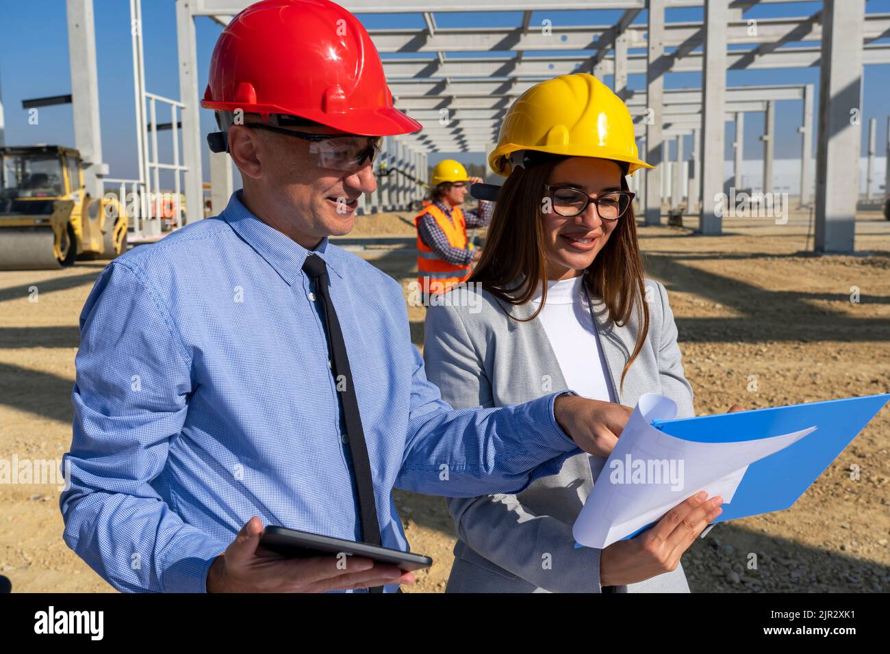 Man and Woman in Hardhats Disscus a Construction Project on Site ...