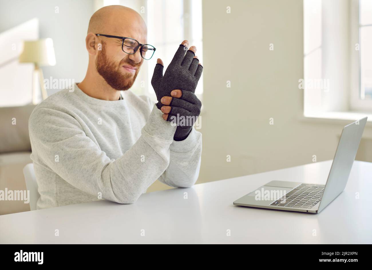 Man with rheumatoid arthritis kneads his hands on which he wears ...