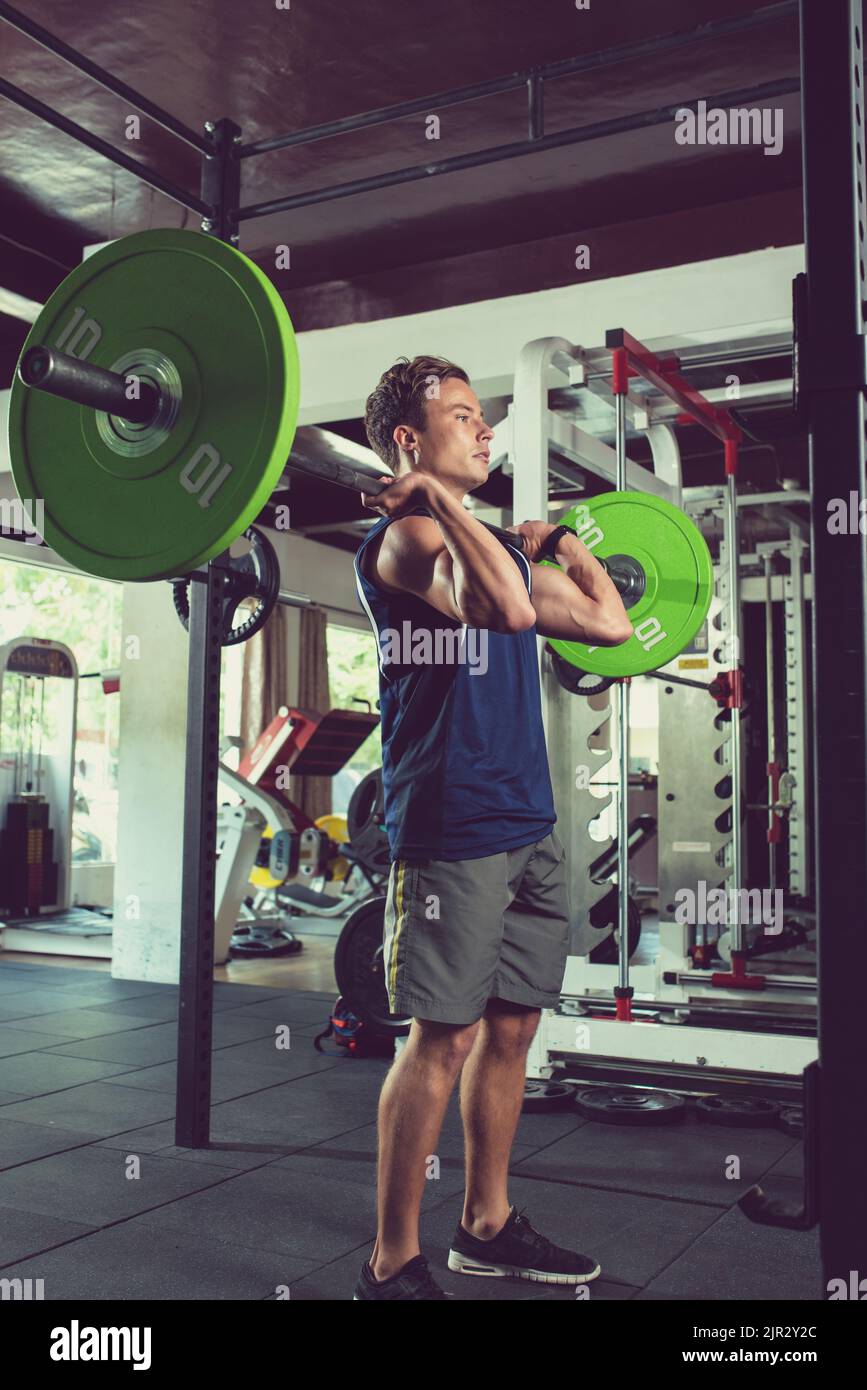 Fit young man lifting heavy barbell in gym Stock Photo - Alamy