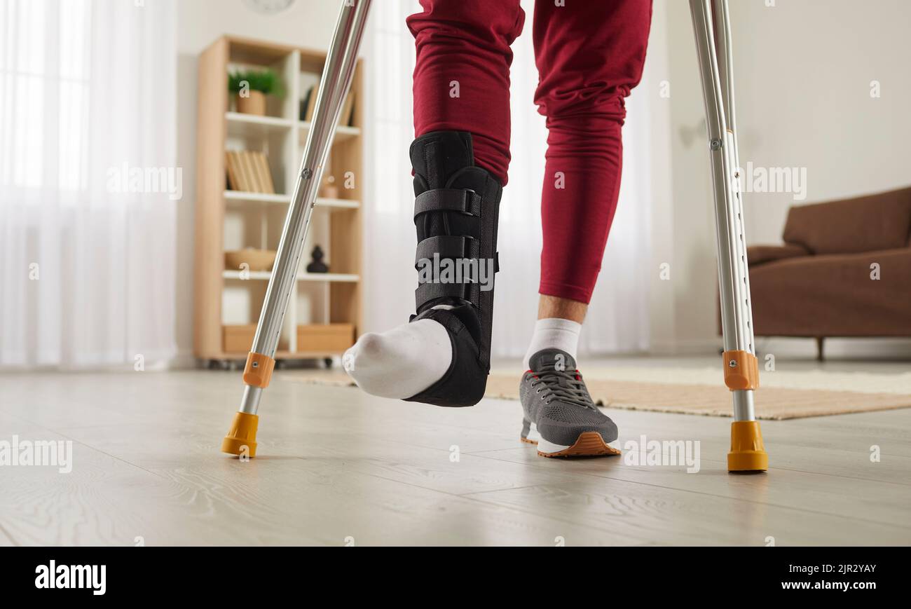 Man with foot or leg injury wearing support brace and walking with ...