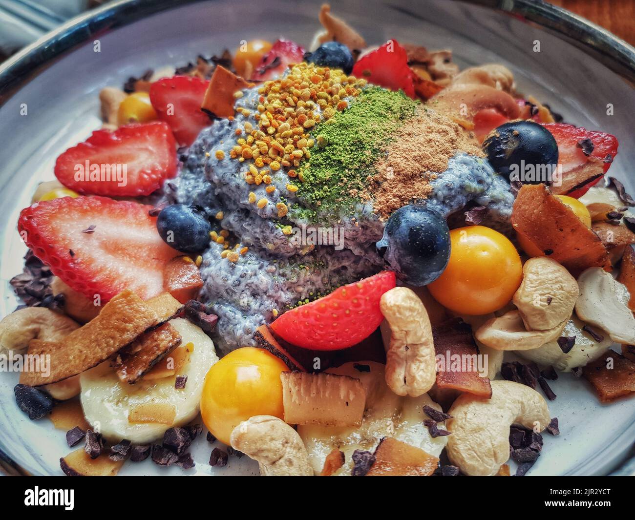 A closeup top view of Acai in the bowl with granola, fruits, and ...