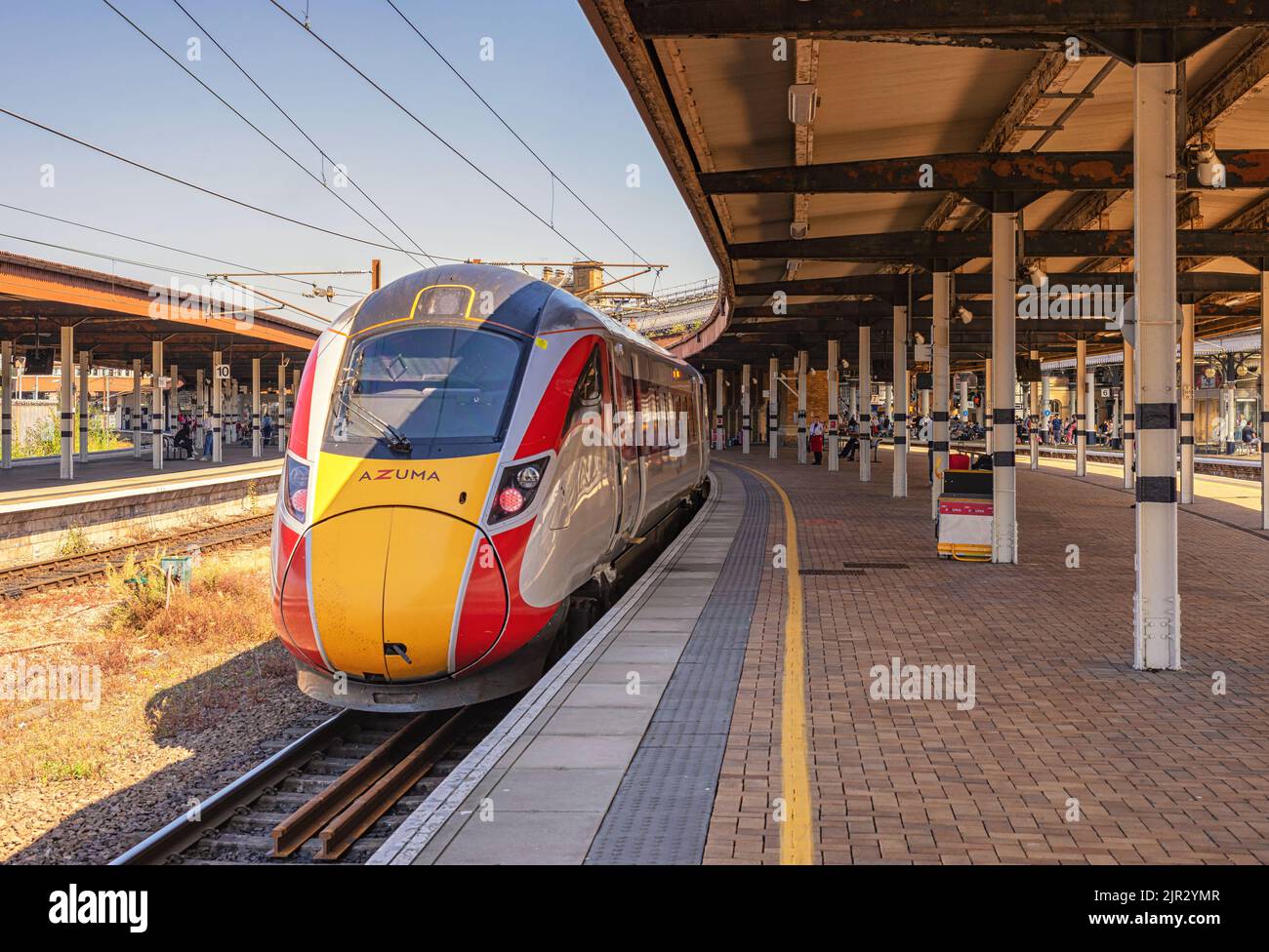 A train rests in the shade of a canopy on a railway station platform. A ...