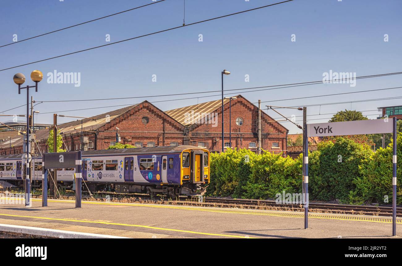 A local train departs a railway station. There is a platform with a ...