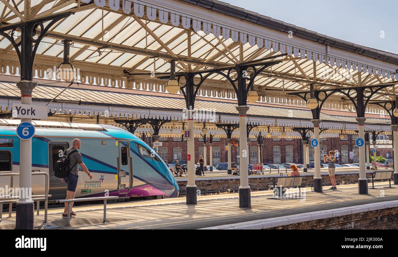 A train rests under an old 19th Century historic canopy. Passengers are ...
