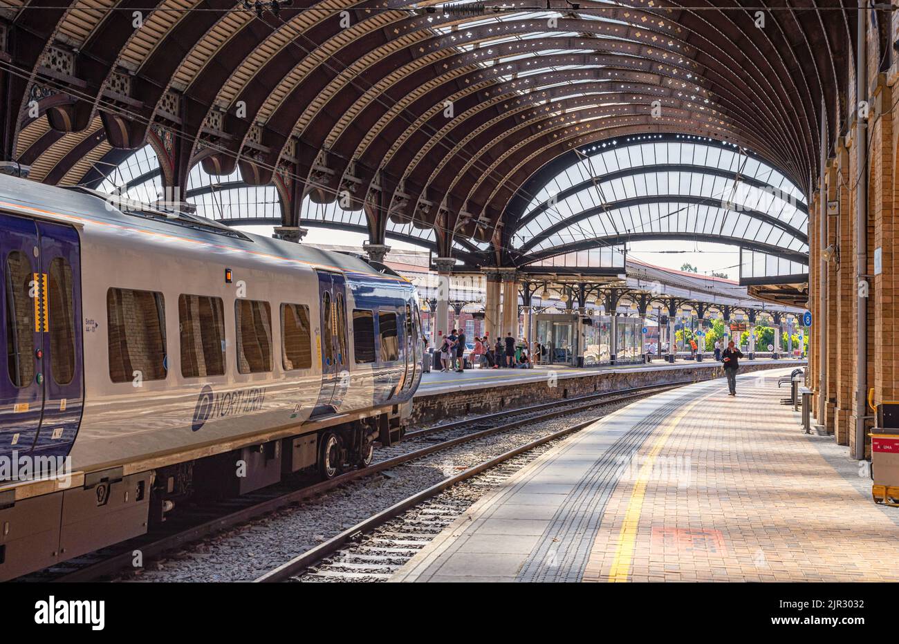 A train rests beside a railway station platform. There are passengers ...