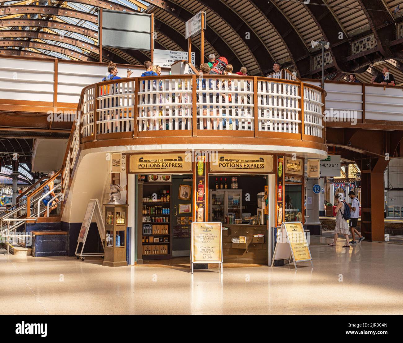 A curving refreshment kiosk is situated under a footbridge in a railway ...