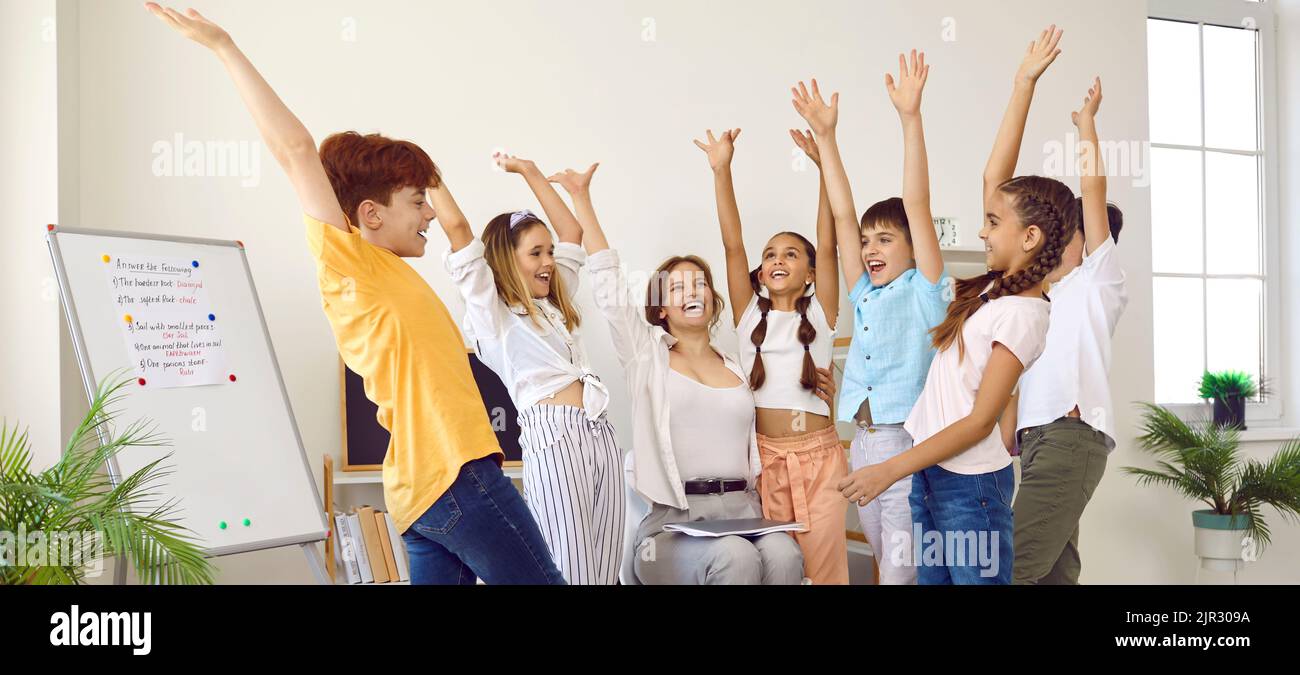 Group of elementary school students and their teacher raising their ...