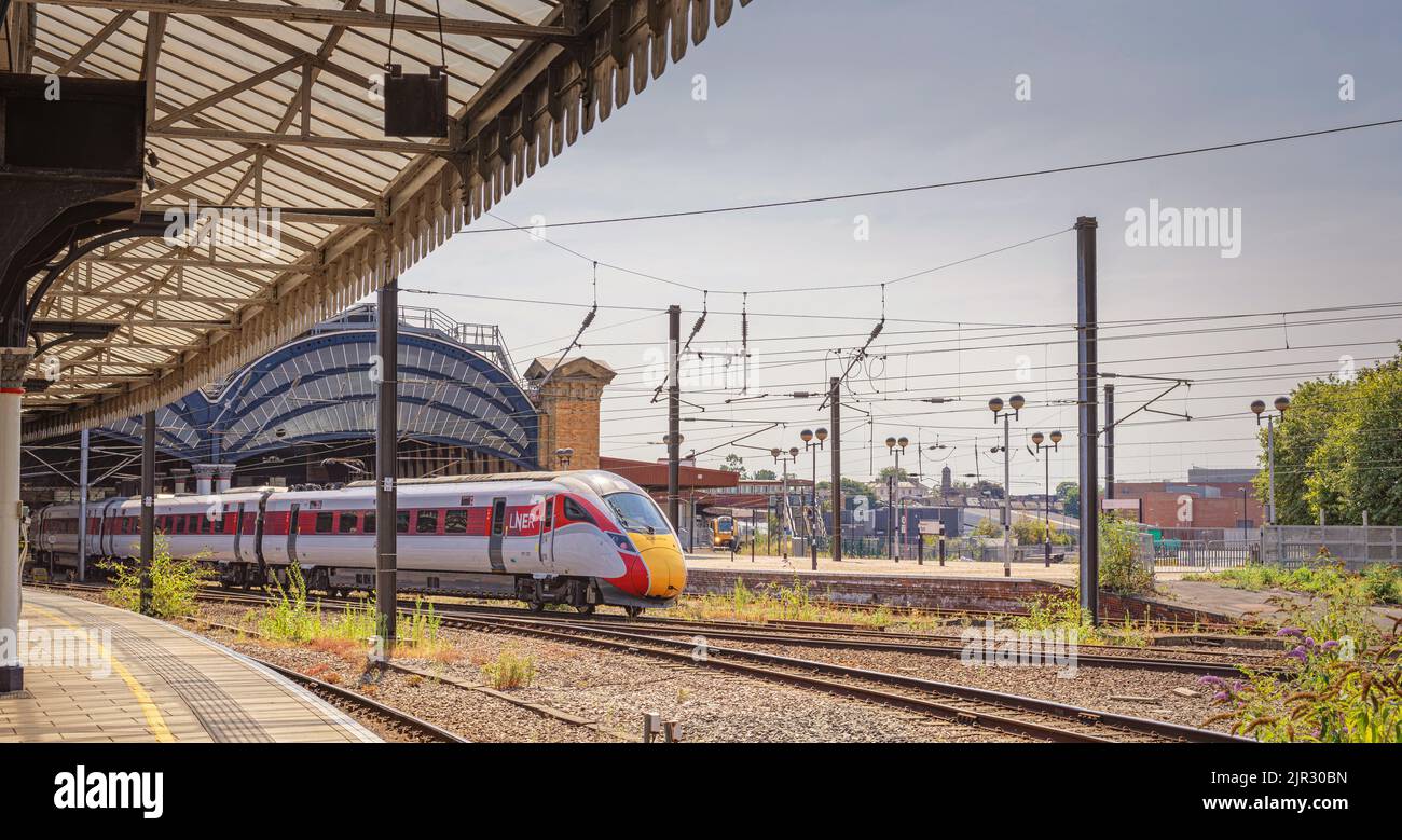 A train leaves a railway station emerging from underneath historic ...