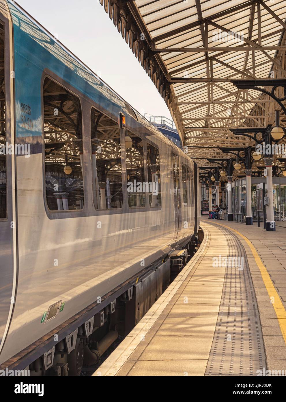 A train rests beside a railway station platform. A historic 19th ...