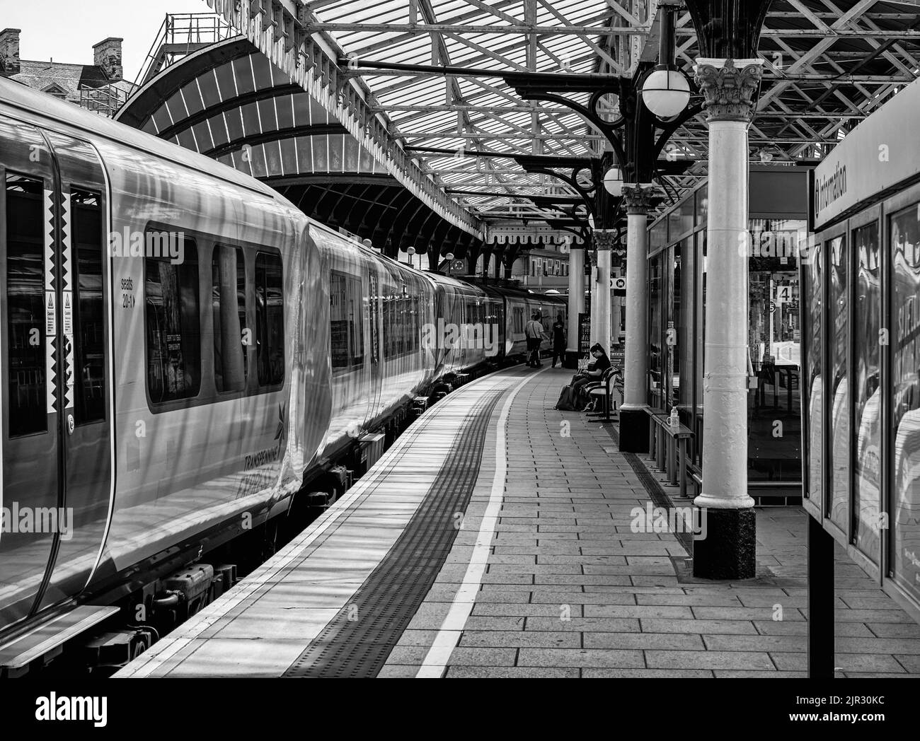 A train rests beside a railway station platform. A historic 19th ...