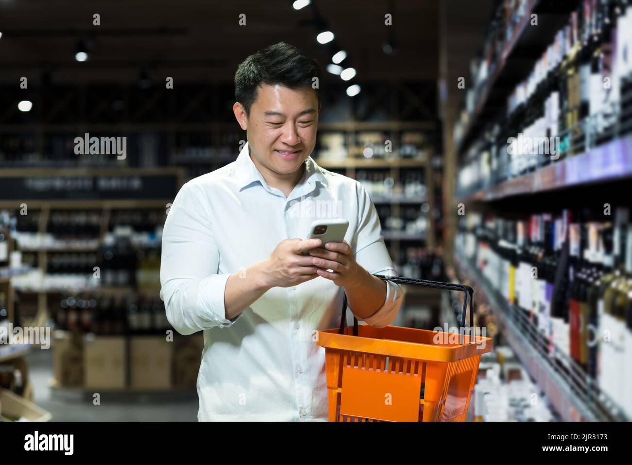 Happy Asian shopper in supermarket using smartphone app to select and ...