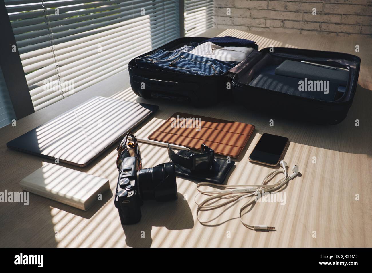 Business gadgets on office table with suitcase with clothes Stock Photo ...