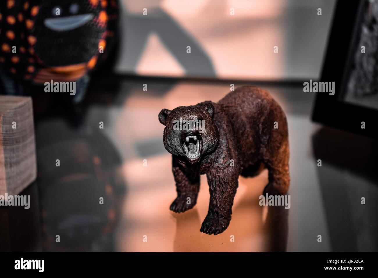 A closeup shot of a small roaring bear figure on a glass table with a ...