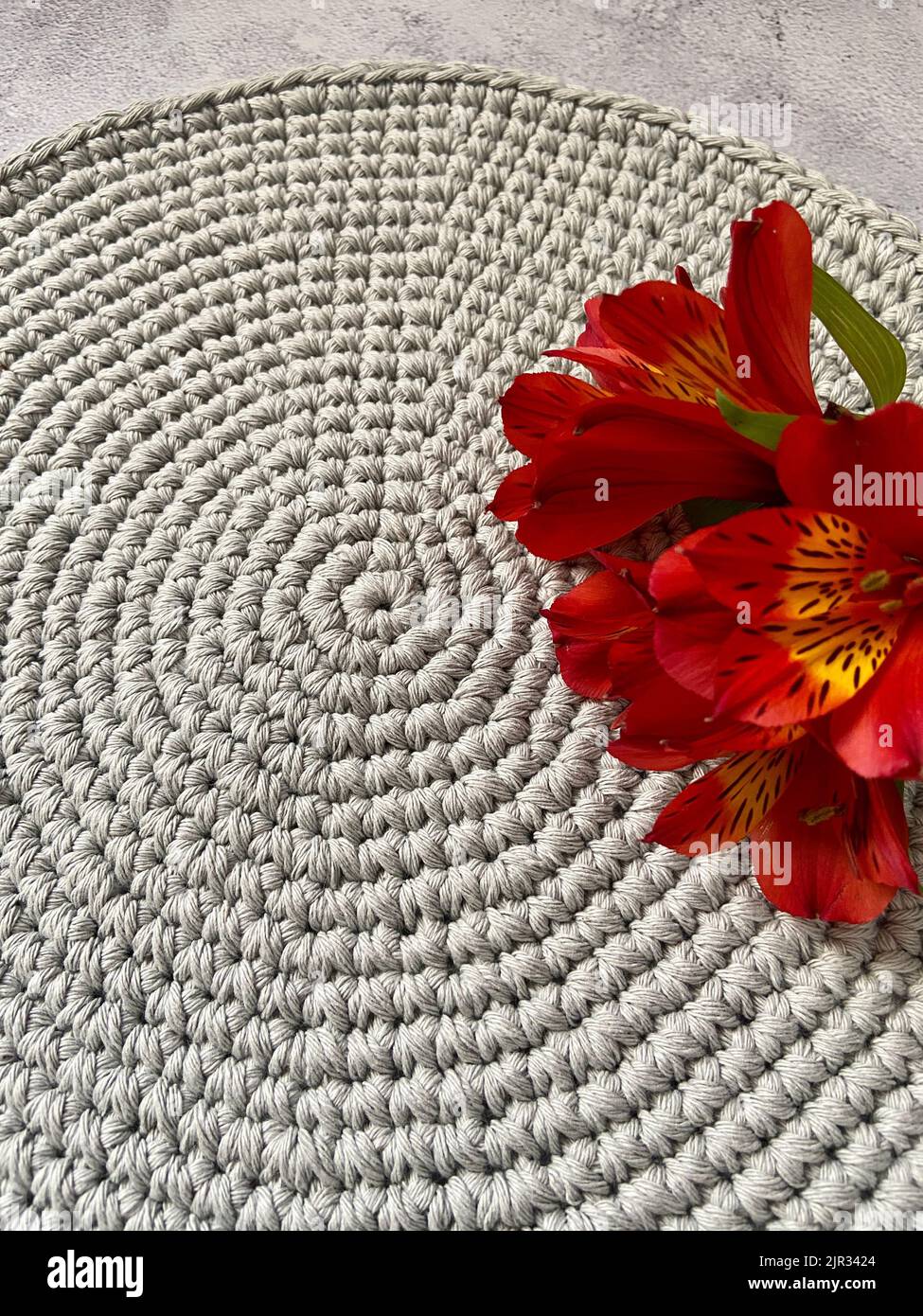 A crochet circle table runner on a wooden table with a princess lily ...