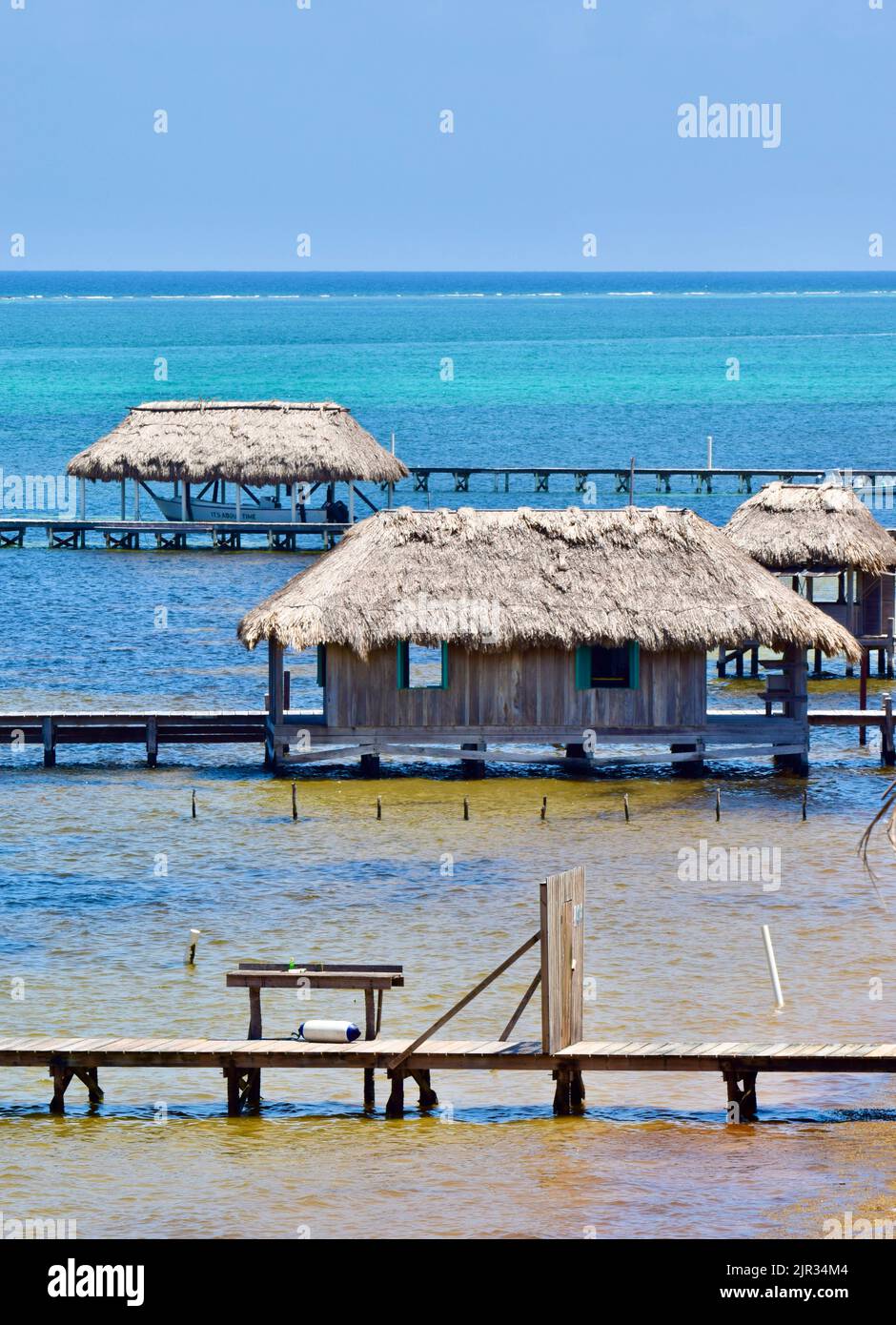 Three palapas on some piers over the turquoise blue waters of San Pedro ...