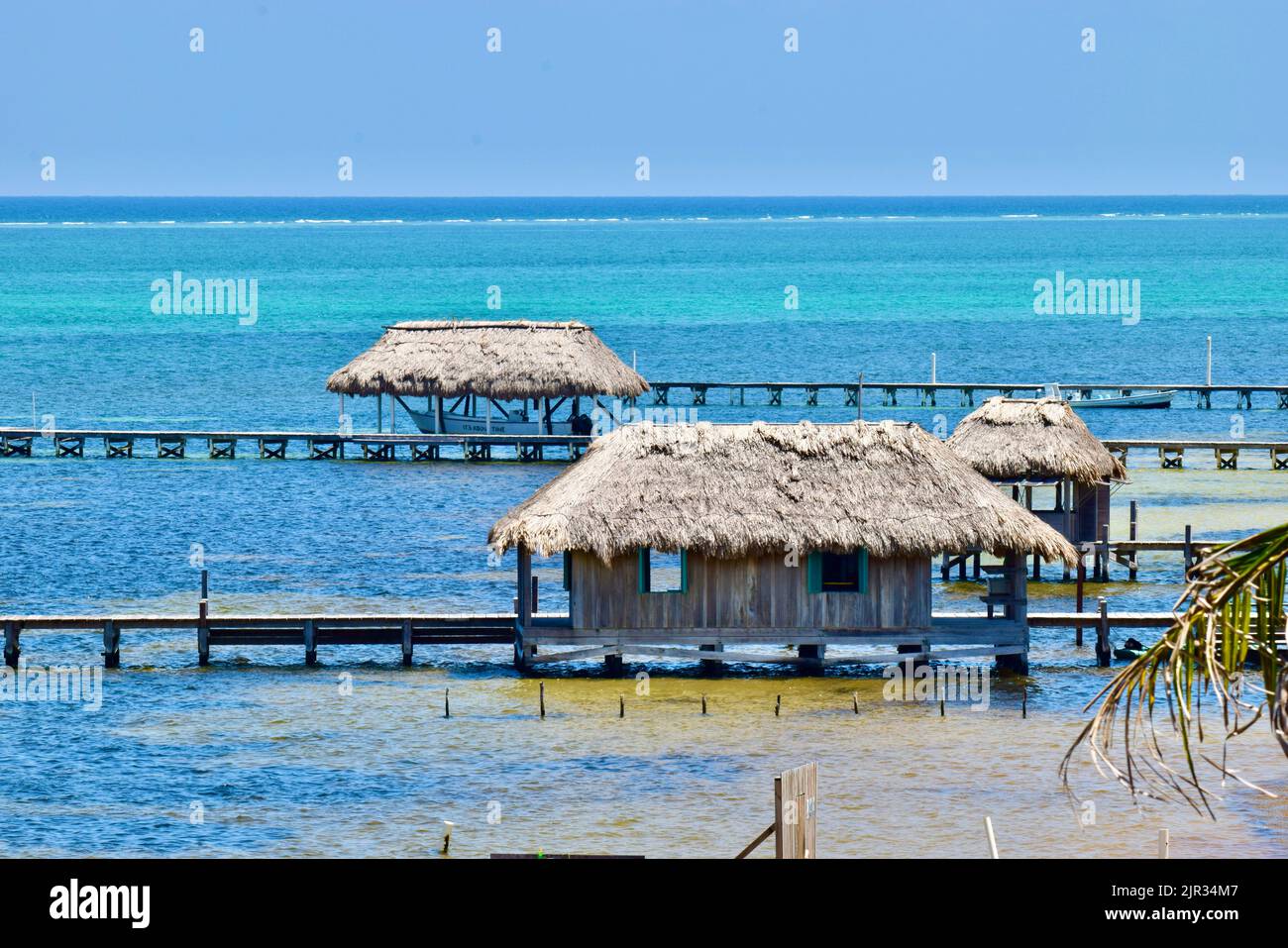 Three palapas on some piers over the turquoise blue waters of San Pedro ...