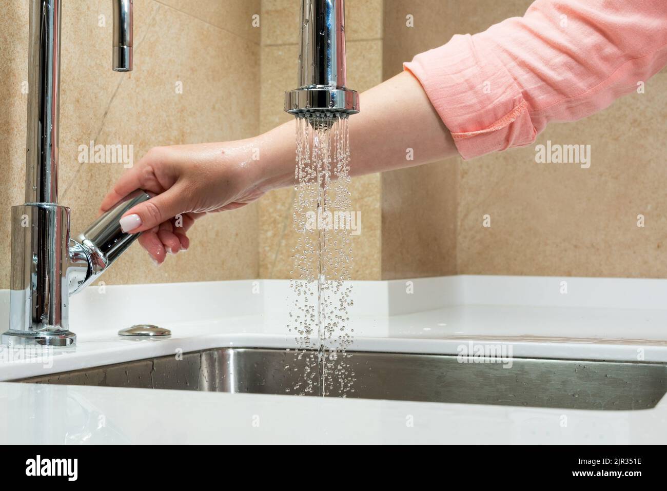 The girl closes the faucet in the kitchen from which water flows as a ...