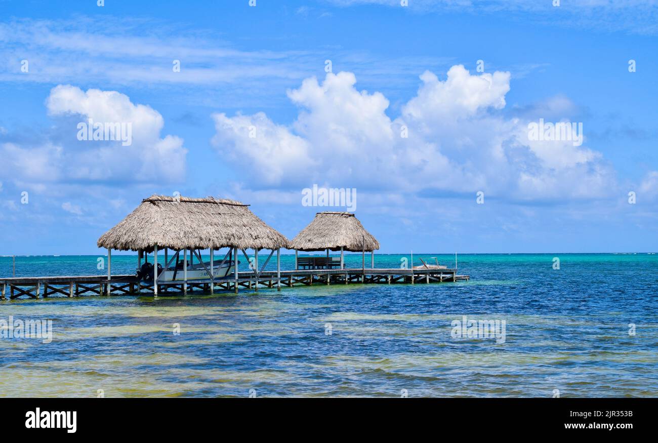 Two palapas on a pier, with a boat under one of them, on a calm, clear ...