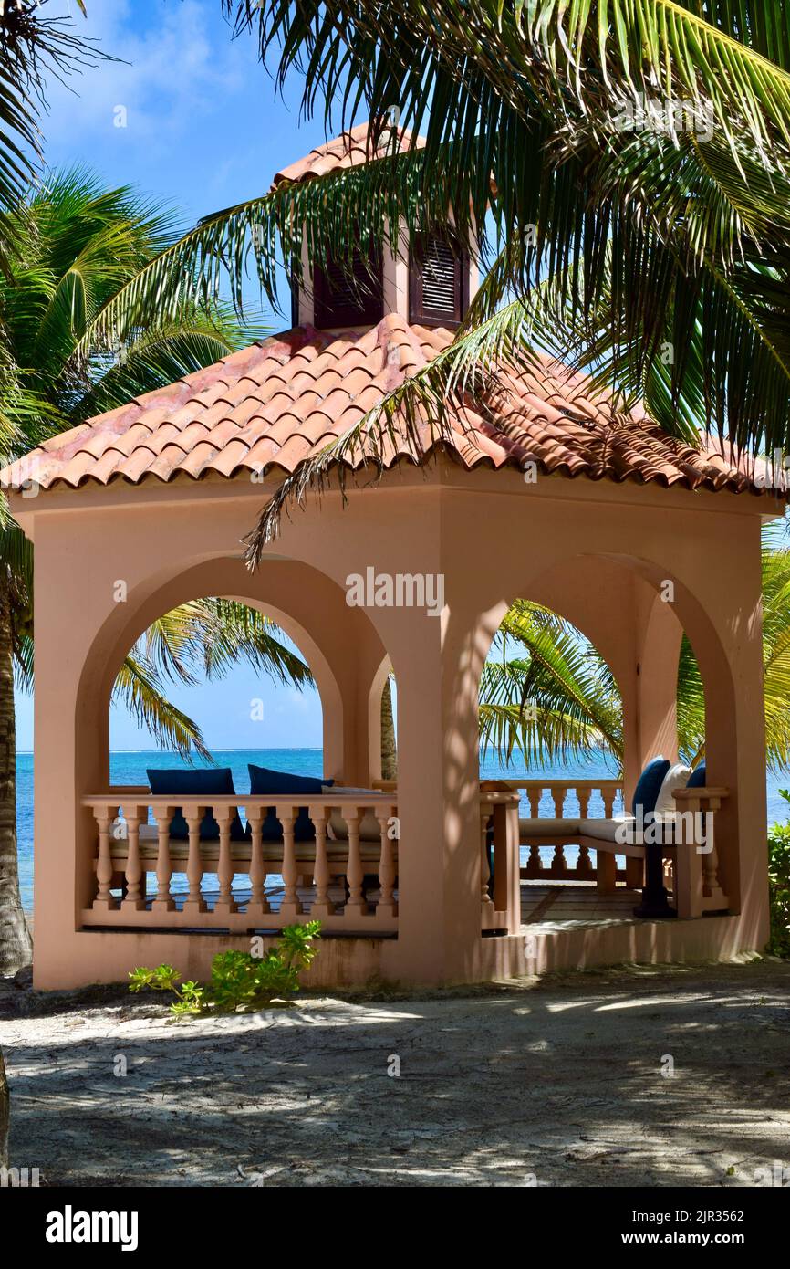A cute gazebo on the beach, among palm trees, overlooking the water on ...