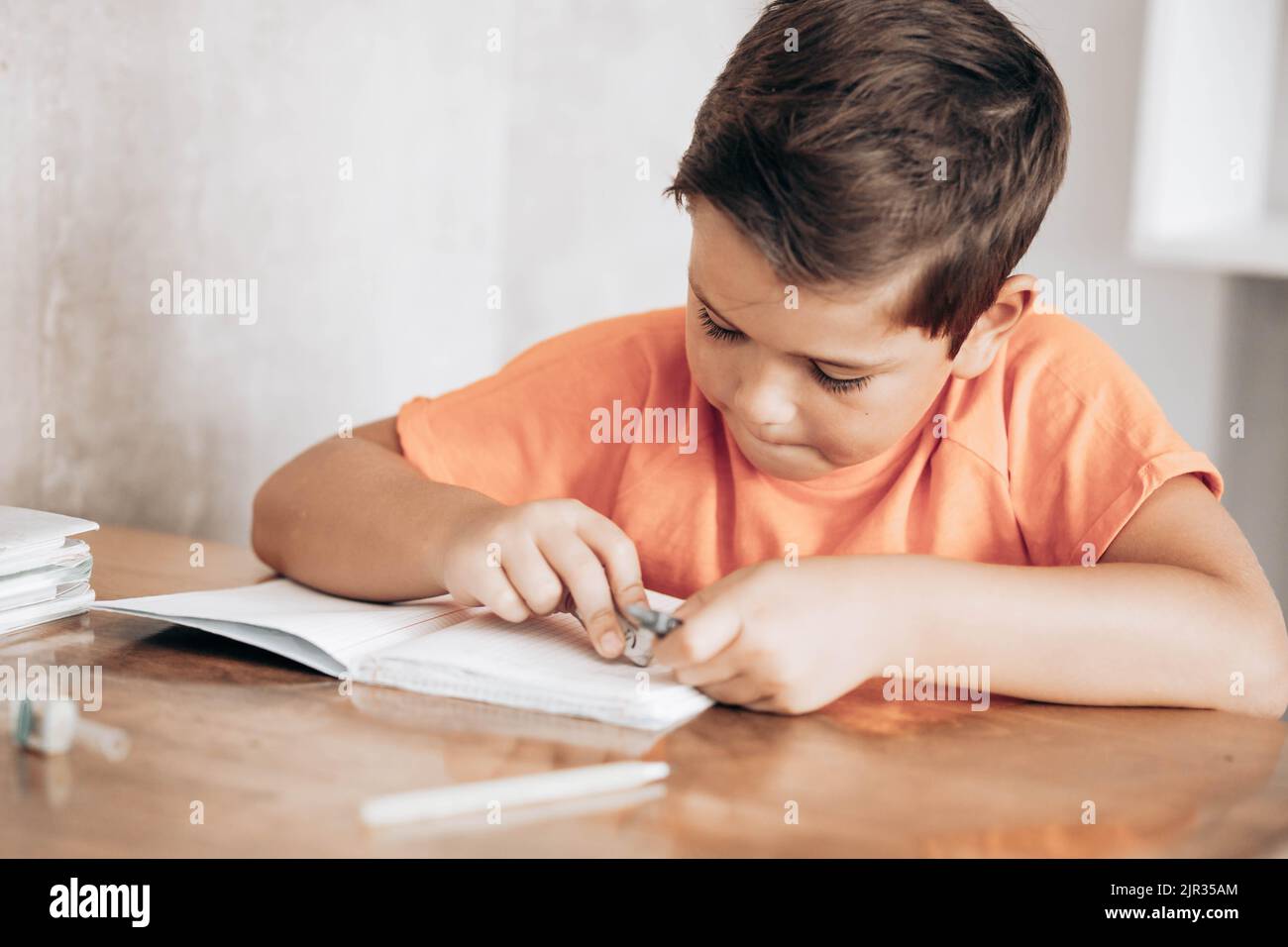 Little school boy doing homework, sitting at the table Stock Photo - Alamy