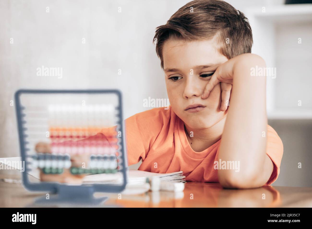 Little school boy doing homework, learning math with abacus, sitting at ...