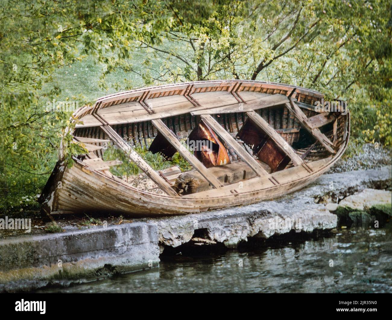 An old wooden boat on the shore with background of trees and forest and ...