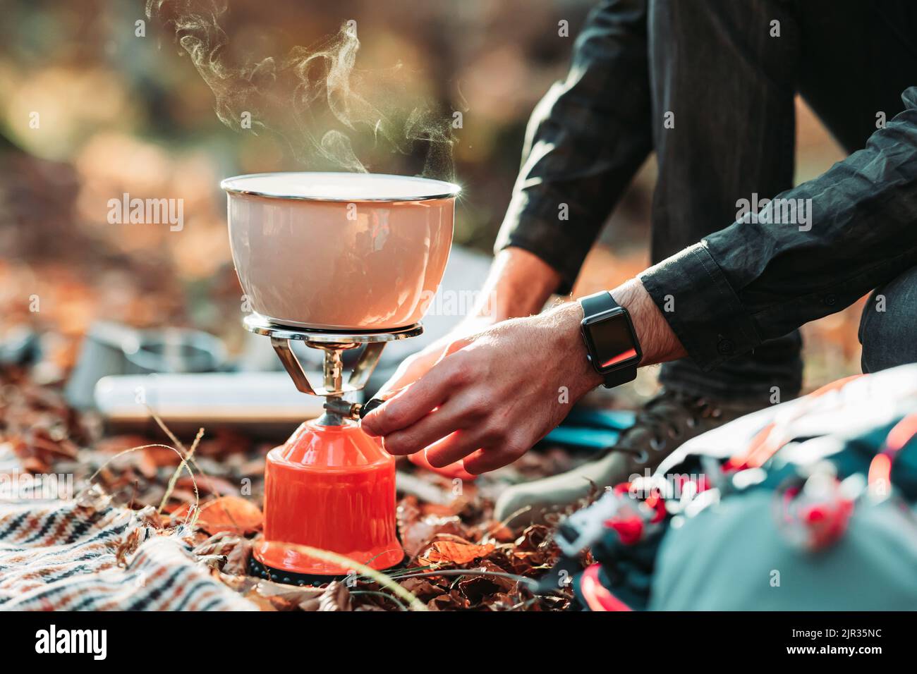 Male hand preparing soup on portable gas stove Stock Photo - Alamy