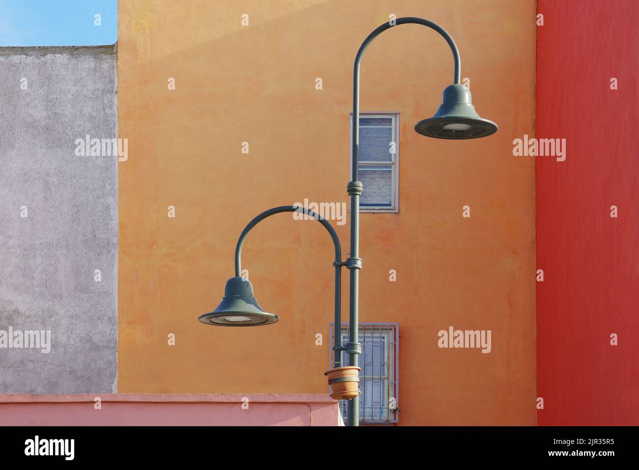 A city street lamp with a backdrop of colorful houses and a patch of ...