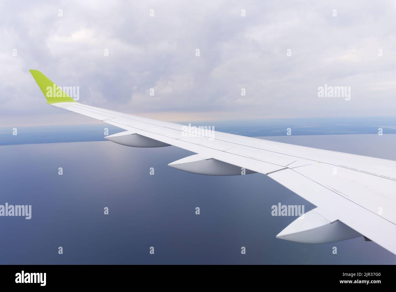 Wing of an airborne airplane ocean below. the plane flies over the ...