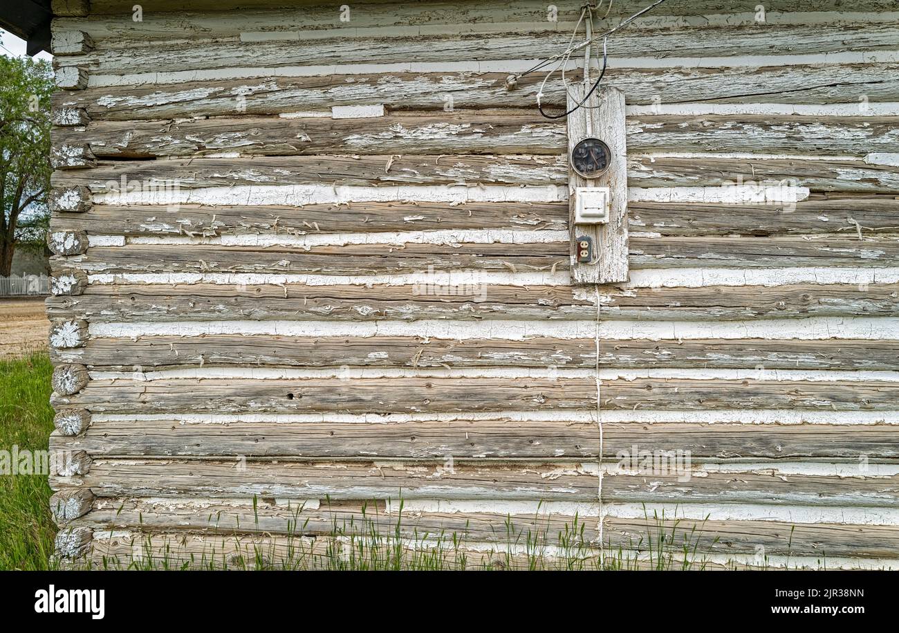 An electric meter and conduits on the exterior wall of an old log ...