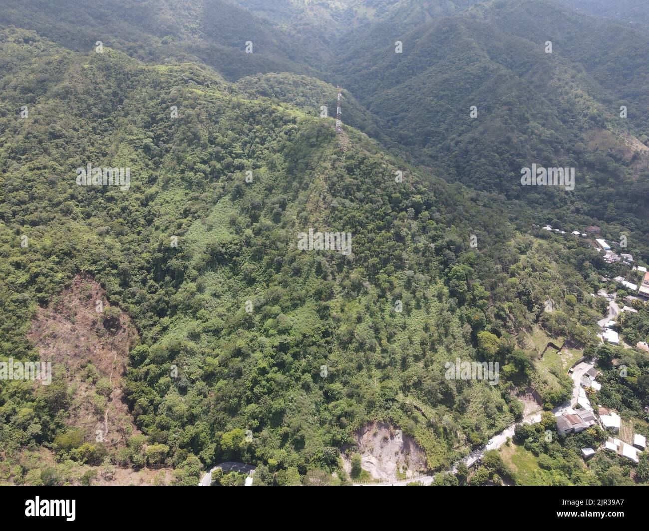 An aerial view of forested mountains next to roads and small houses ...